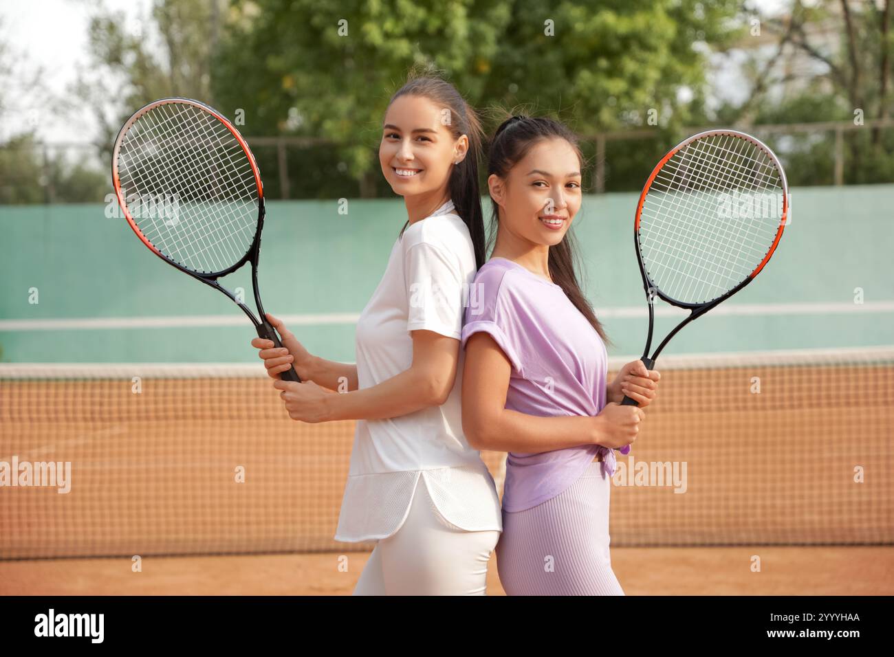 Pretty young women with tennis rackets on court Stock Photo - Alamy