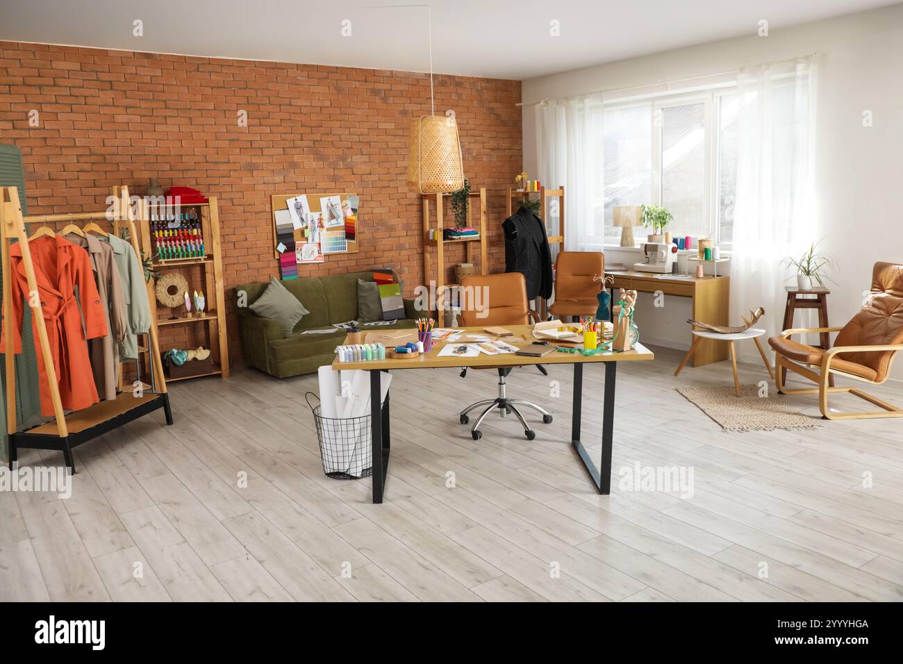 Interior of fashion designer's studio with workplace, sofa and clothes ...