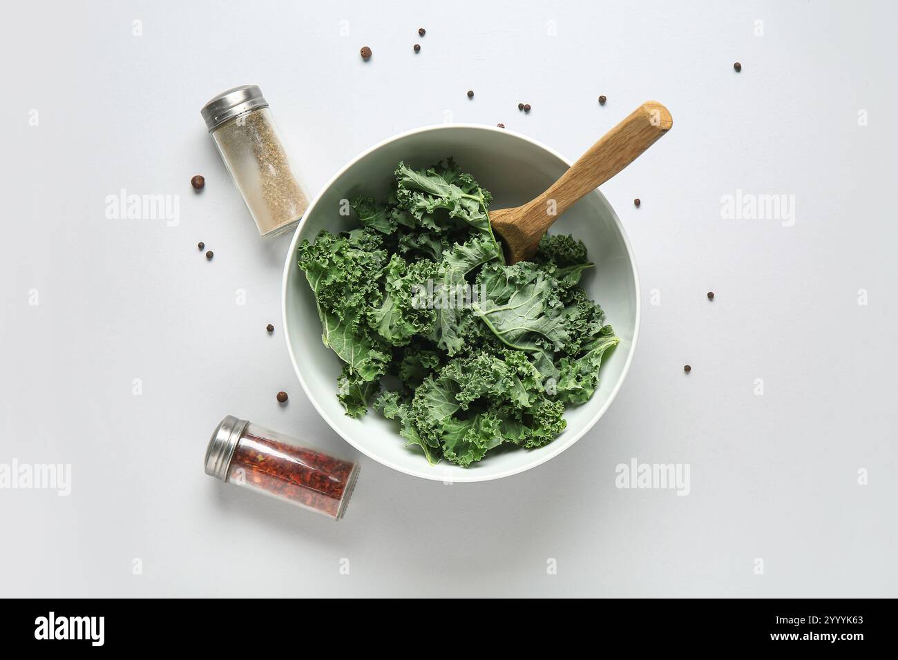 Bowl with fresh leaves of kale cabbage and spices on grey background ...