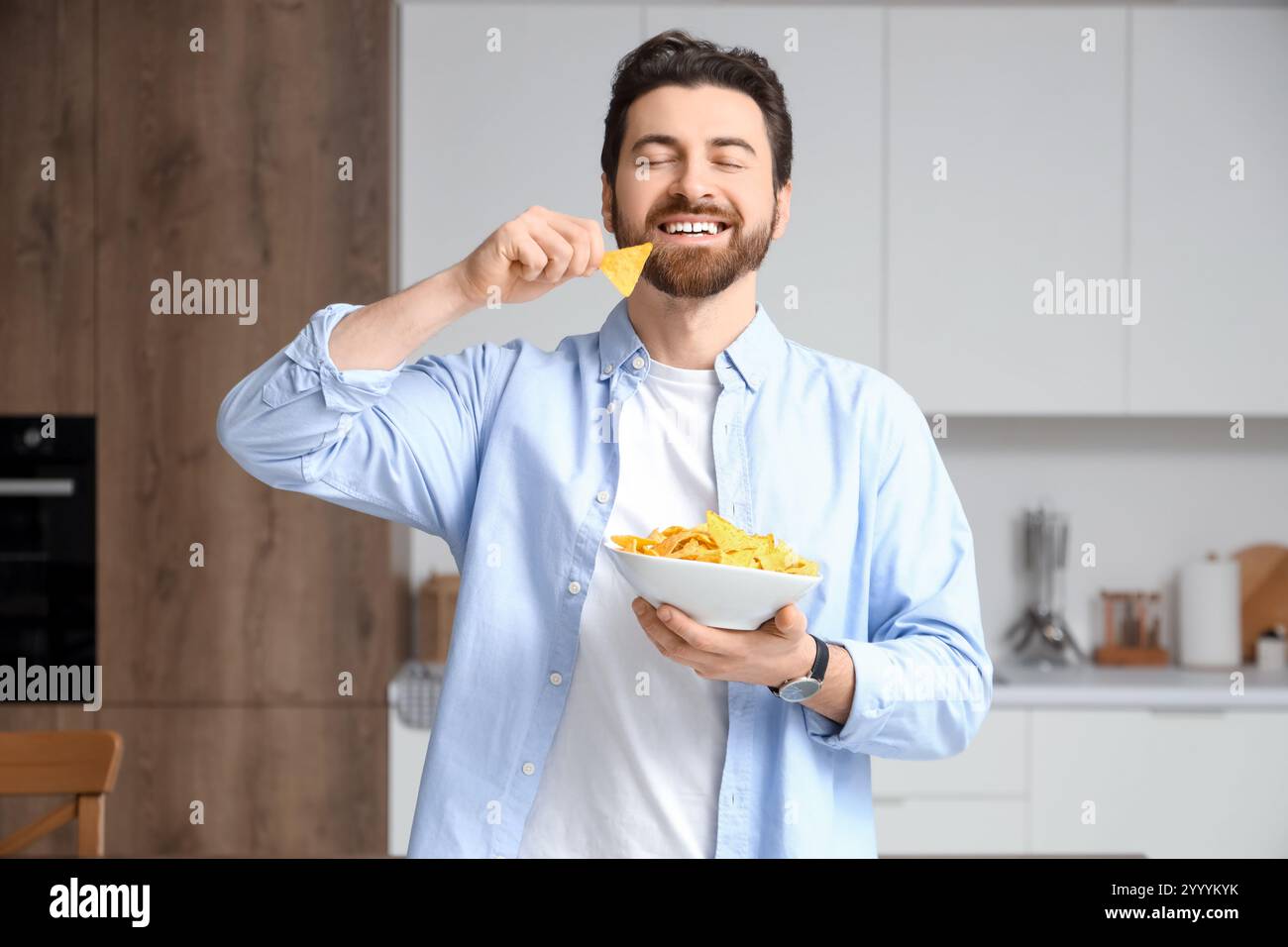 Man eating tasty nachos in kitchen Stock Photo - Alamy