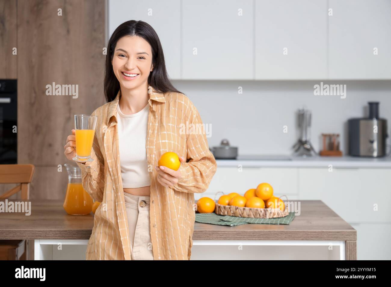 Young woman with sweet orange juice in kitchen Stock Photo - Alamy