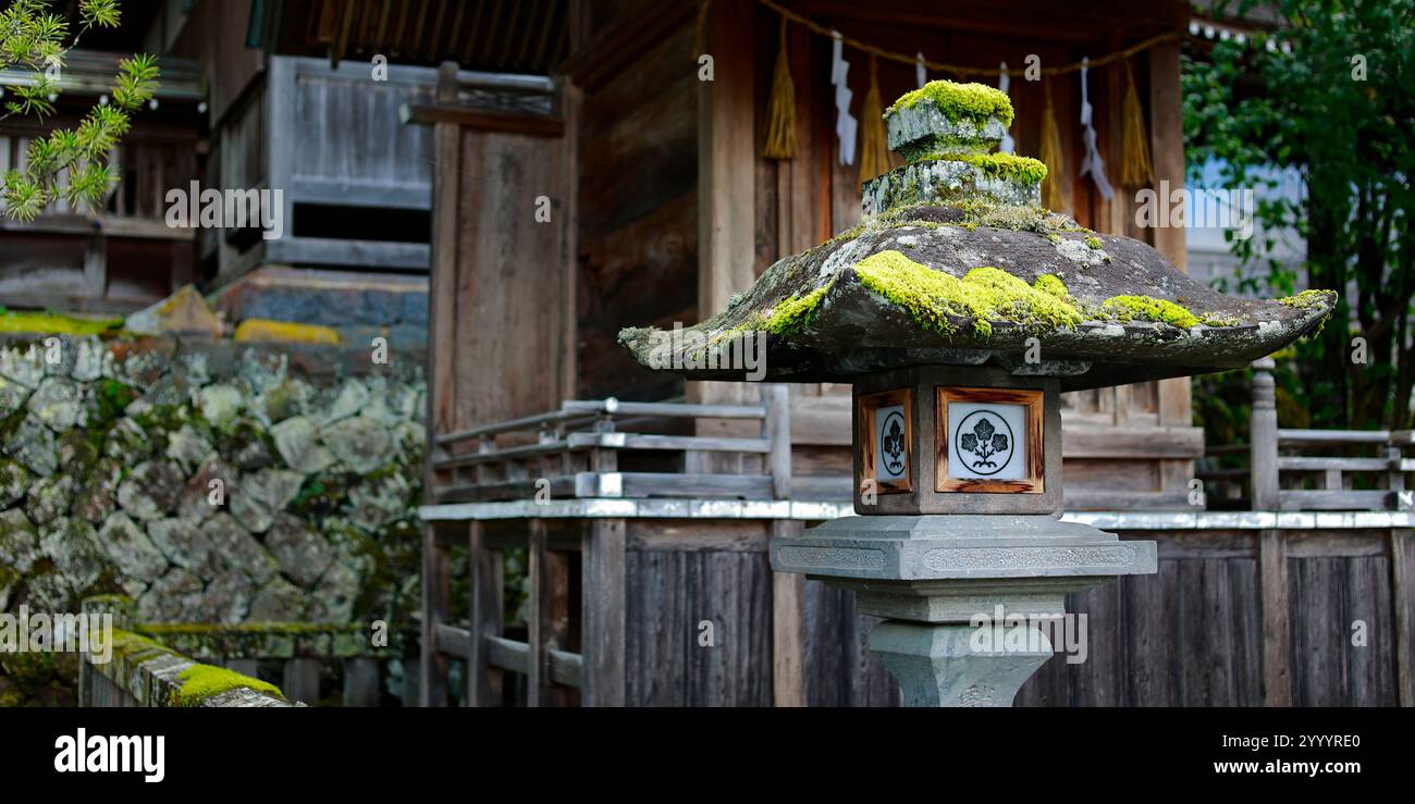 Traditional japanese stone lantern with moss in front of stone wall ...