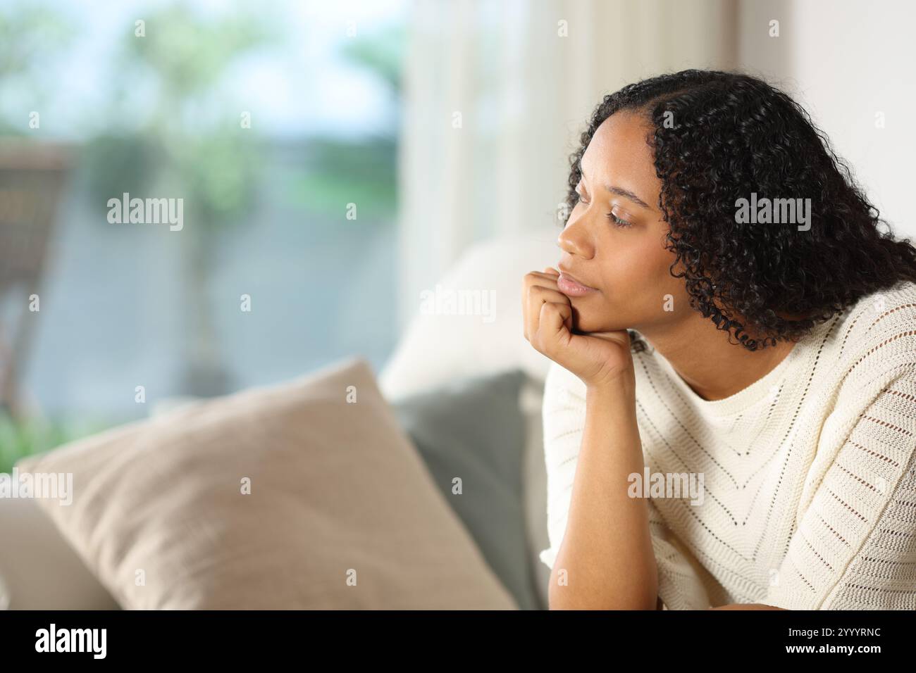 Distracted black woman thinking sitting on a sofa at home Stock Photo ...