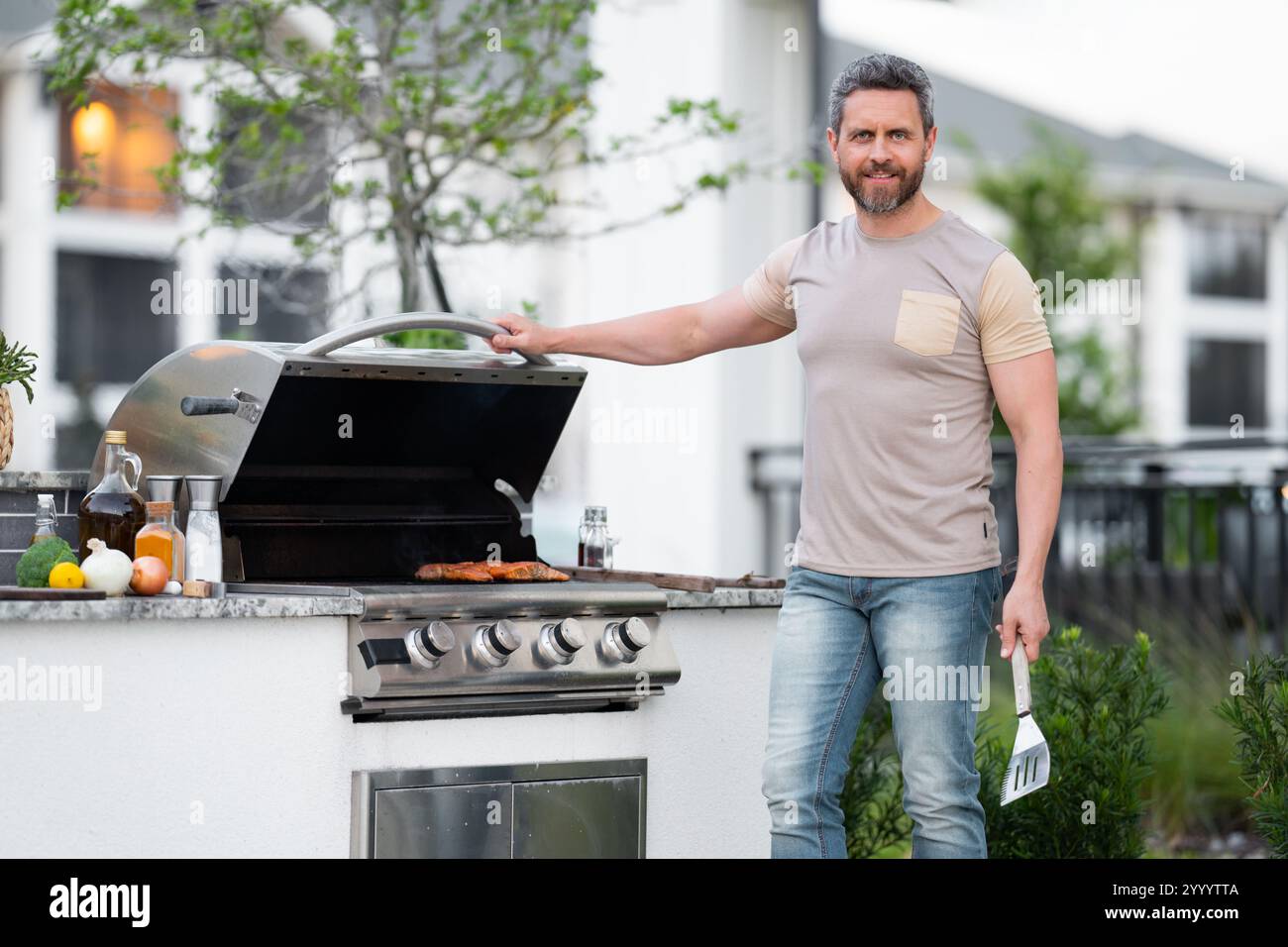 Handsome smiling hispanic man making barbecue at backyard. Picnic ...