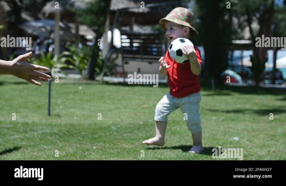 Cute little boy playing with a soccer ball running to his mother in a ...