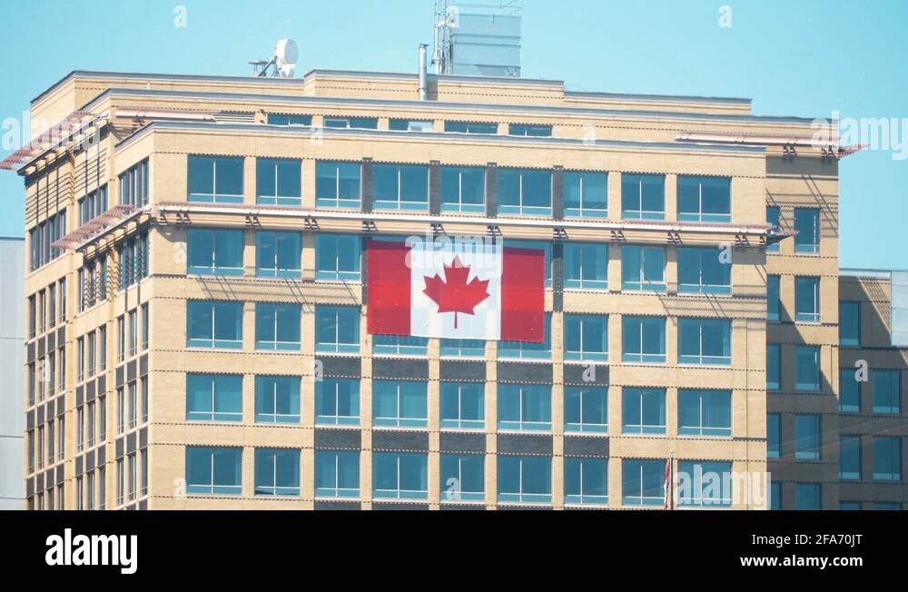 A Canada flag hanging on the side of a tall office building in downtown ...