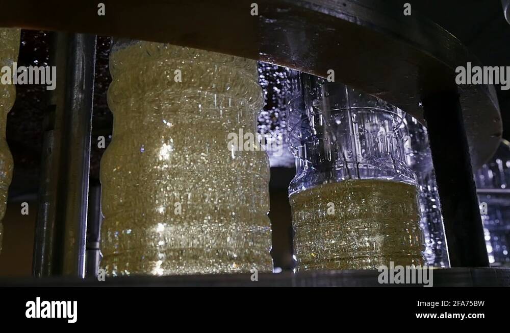 Splattering sunflower oil pouring into plastic bottles on an oil plant ...