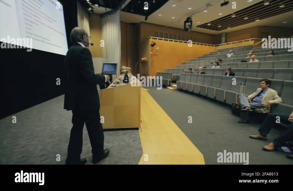 Professor giving a presentation to a class in a large classroom with ...