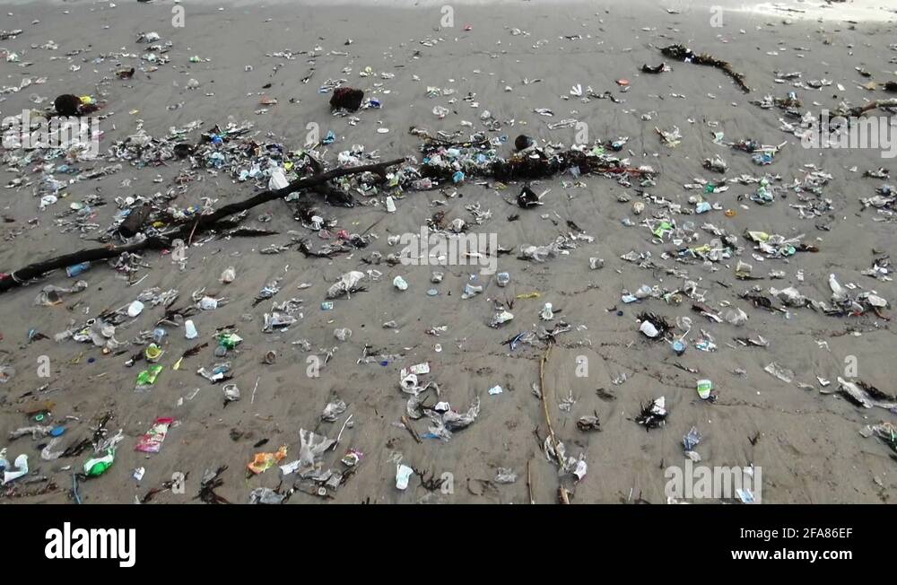 Tilt up shot from a heavily polluted beach to the ocean, as waves ...