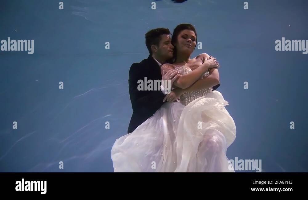 romantic lovers pair are swimming inside water of swimming pool ...