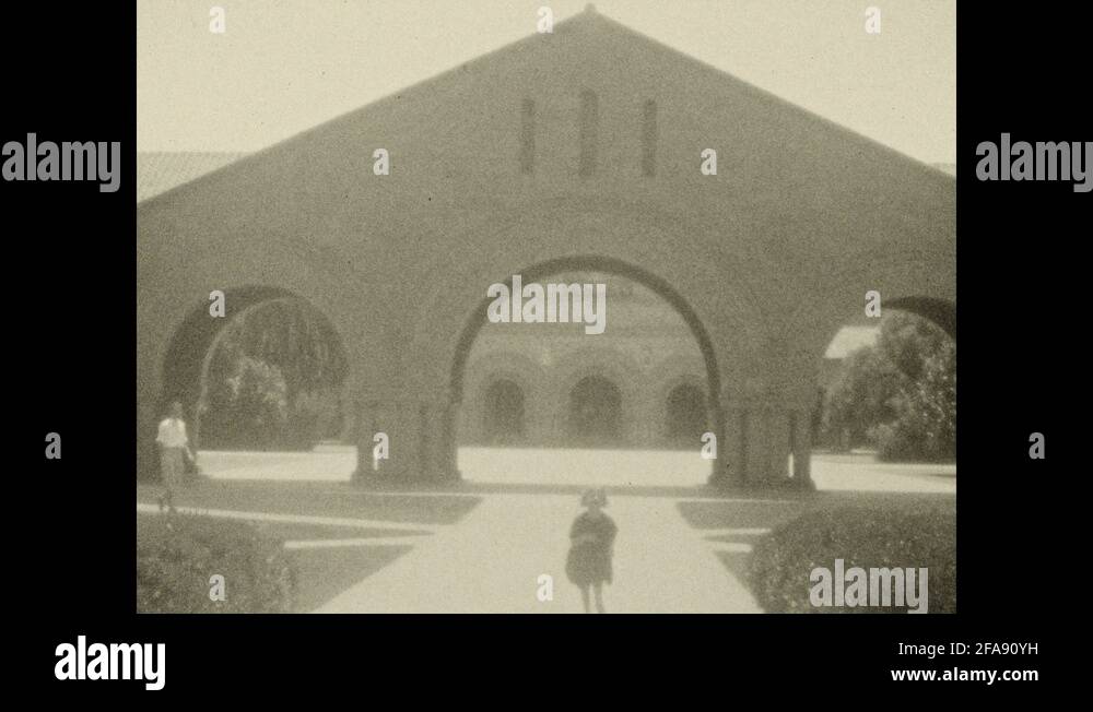 1920s: Girl runs down path in front of archway. People walk towards ...