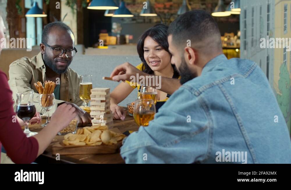 Four friends playing Jenga in bar Stock Video Footage - Alamy