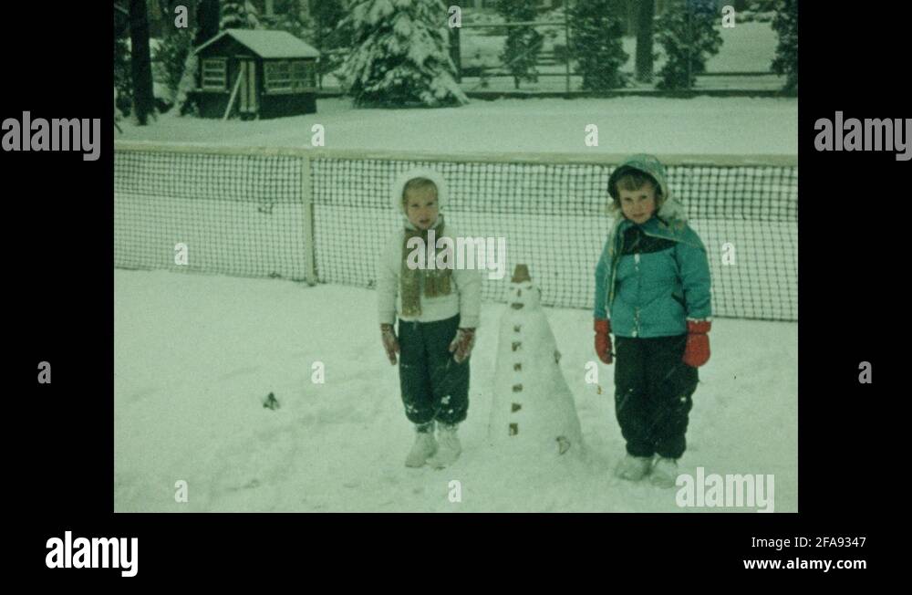 1950s: Little girls sit next to snowman and clap hands. Little girls ...