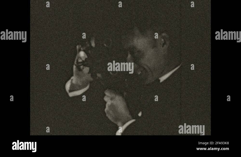 1920s: UNITED STATES: man with cine camera. Family sit on sofa. Family ...