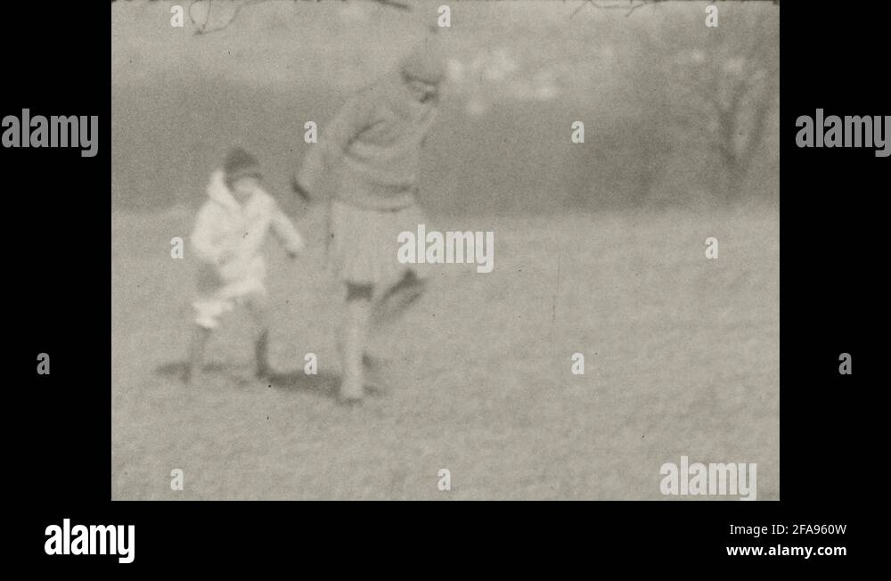 1920s: UNITED STATES: lady and girl run across field. Man points into ...