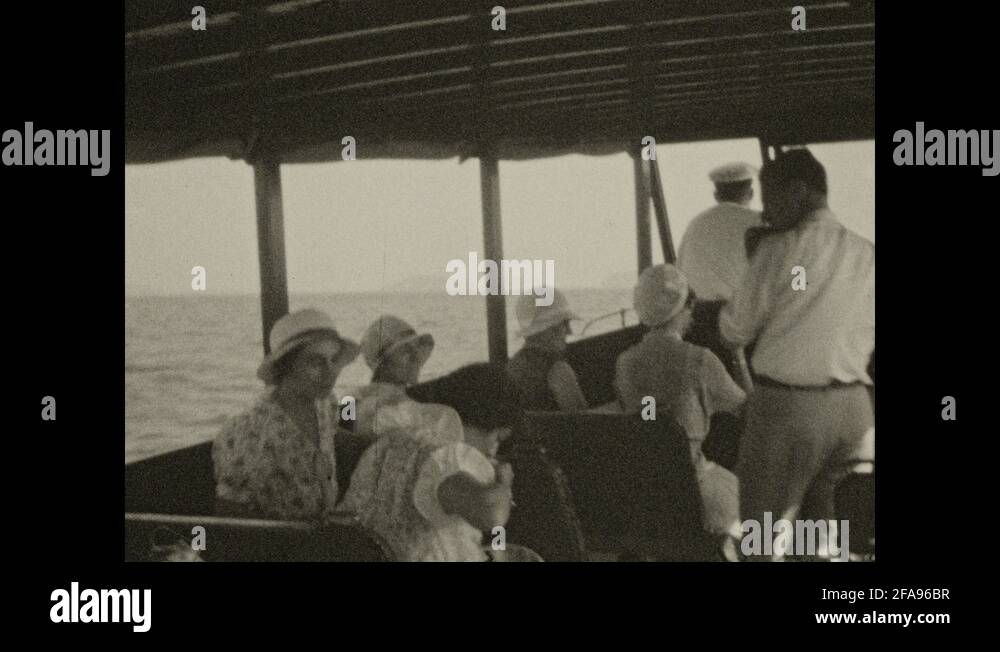 1920s: Passengers sit in chairs on open air ferry deck. Passengers ...