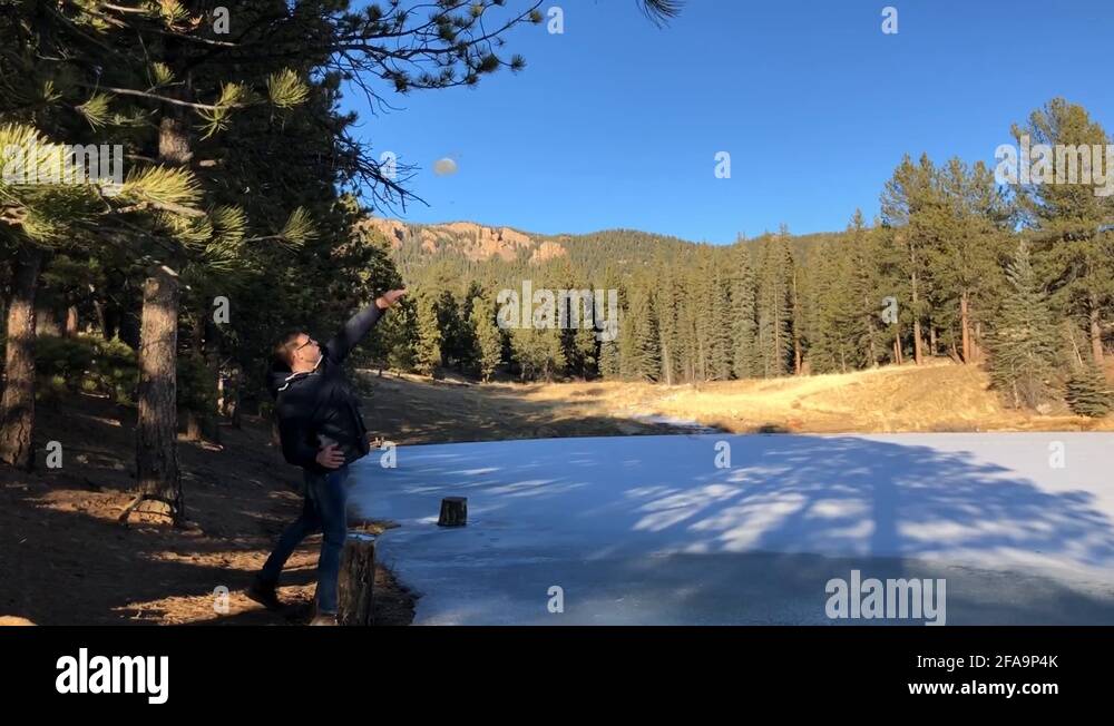 Man throwing ice onto huge frozen lake Stock Video Footage - Alamy