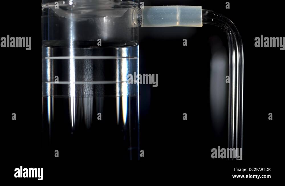 Air bubbles surfacing through water in a see through tube as part of a ...