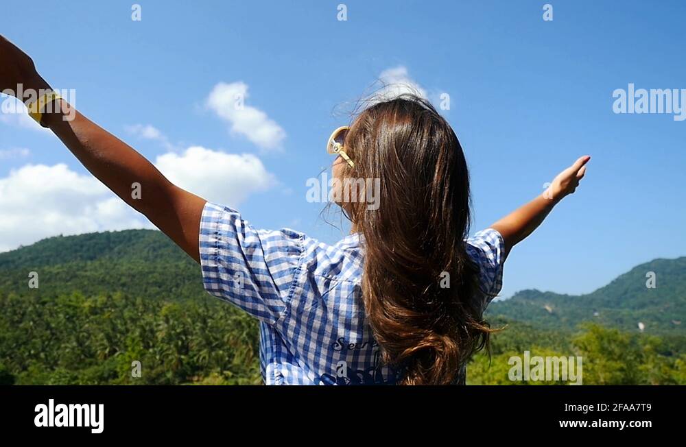 Hiker woman rises up hands in the mountain in slow motion. Back view ...
