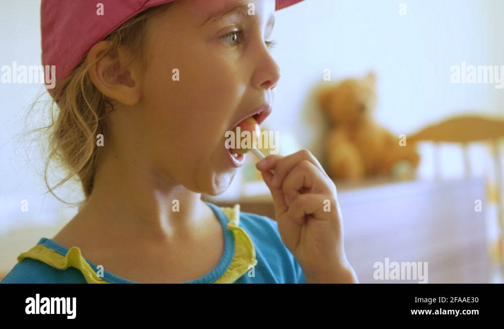 Little girl enjoying a lollipop while staring at camera. Child eating ...
