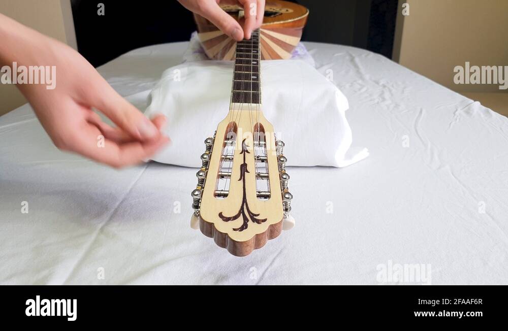 Close-up hands of young man tuning a traditional stringed instrument ...