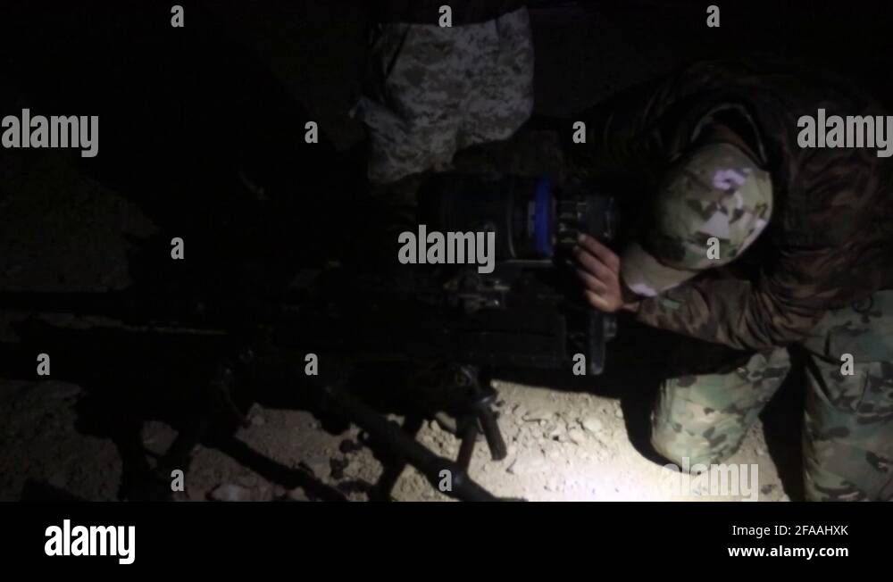 Soldier adjusting machine gun with torchlight for night time live fire ...