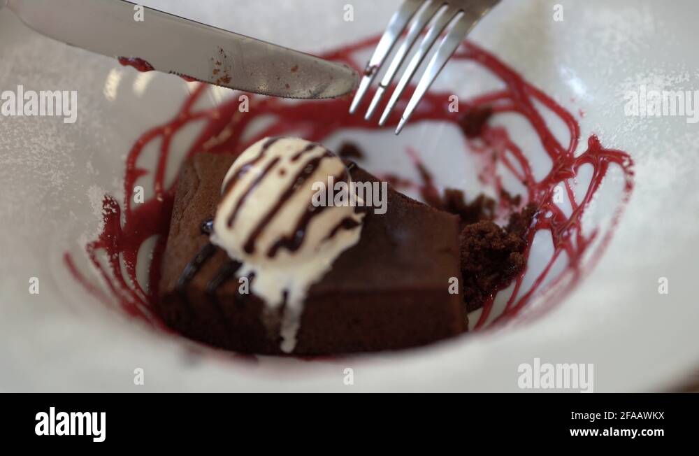 Close scene as a girl is cutting her dessert with fork and knife. There ...
