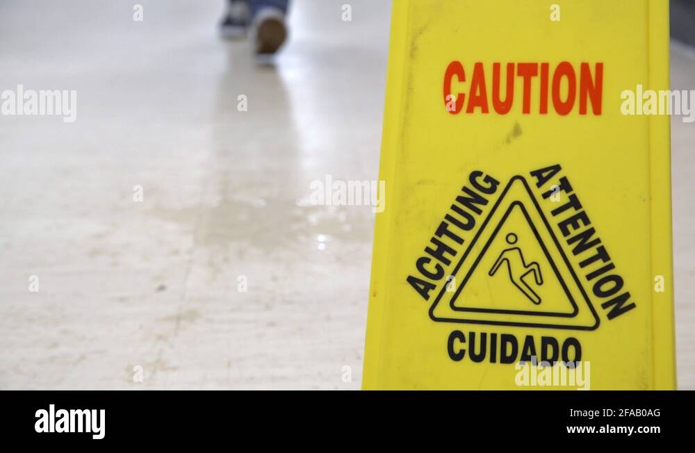 A man slipping on a wet floor in front of a caution slippery sign Stock ...
