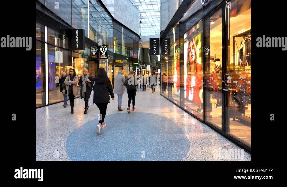 Many people and shoppers walking and shopping in a busy shopping mall ...