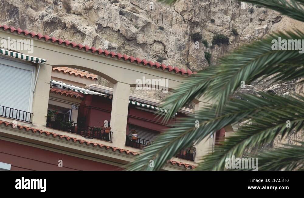 Pan up from a patio and palm tree to reveal an old stone clifftop fort ...