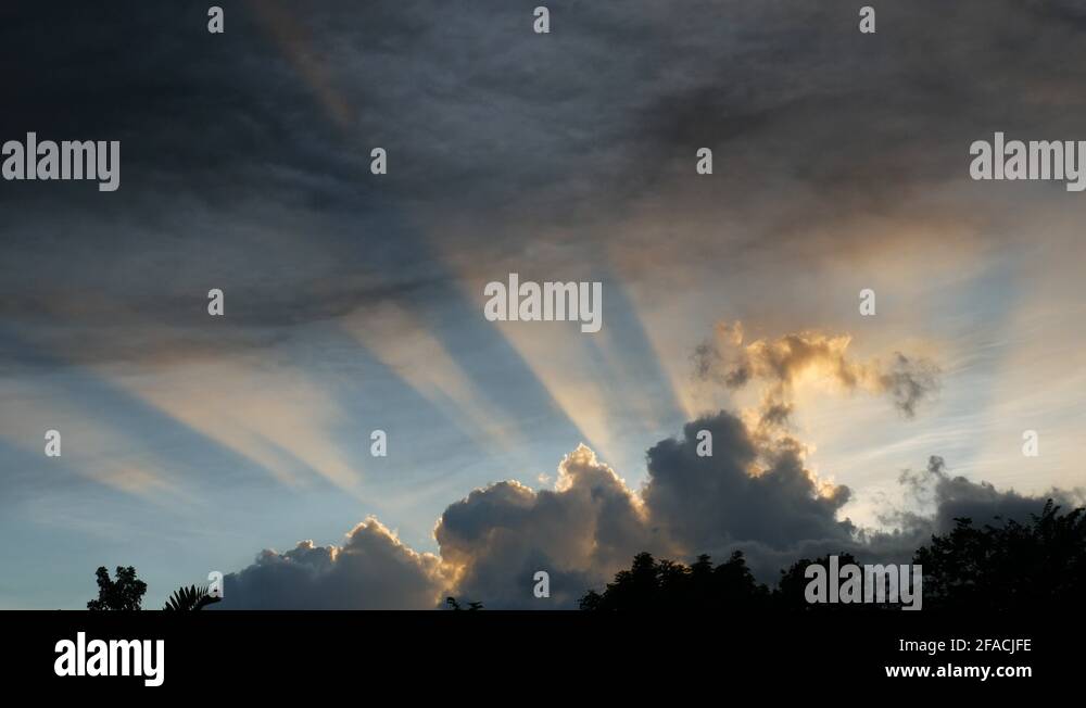 Evening sun rays through clouds and dark smoke cloud from fire covering ...