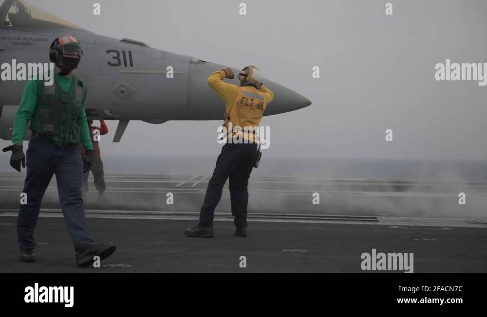 Aircraft handler signals to pilot of F/A-18 Hornet aboard USS John C ...