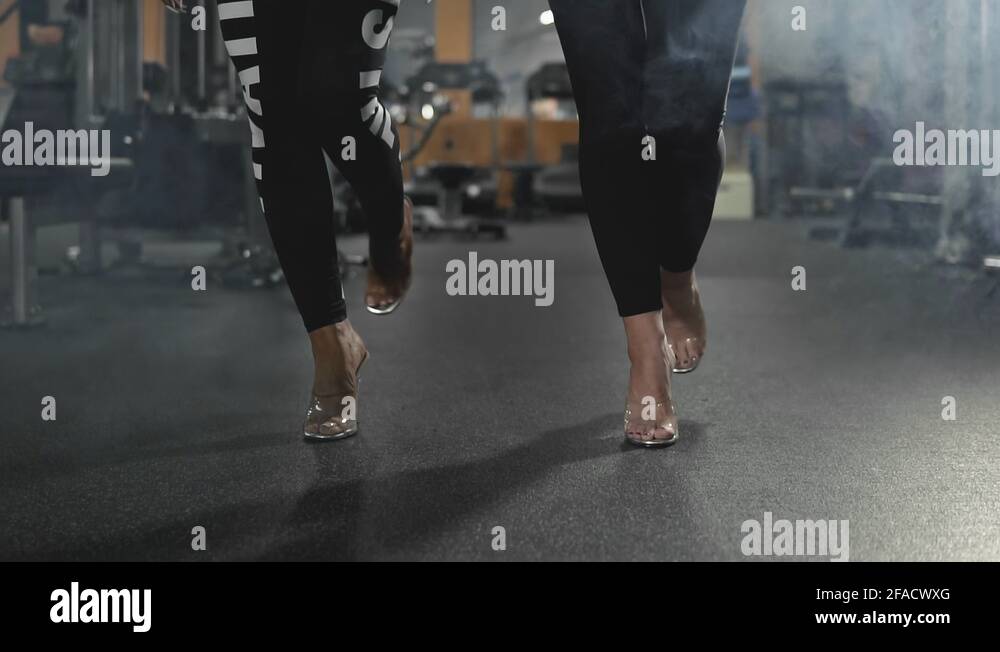 Two fitness bikini blonde girls posing in dark gym in slow motion on ...