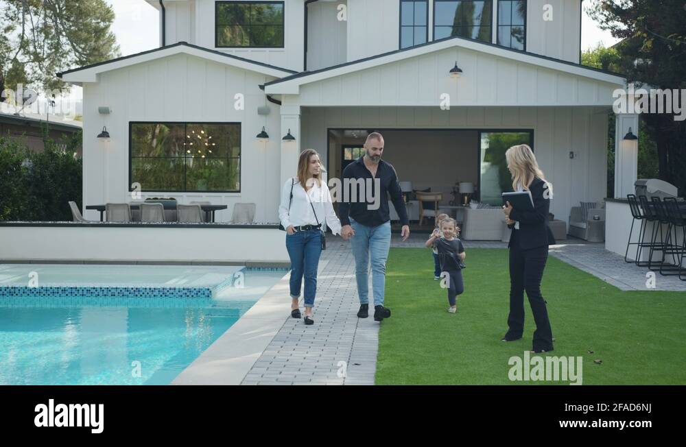 Realtor showing a new modern house to a young family at open house ...