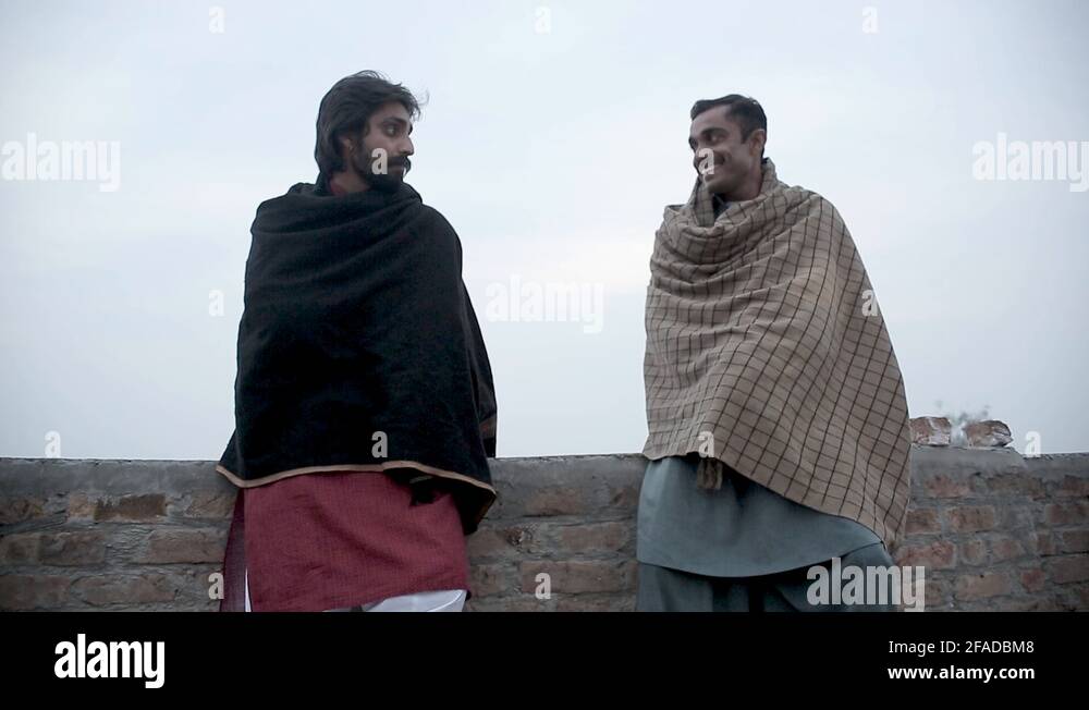 Two male friends talk,smile & give high five in a punjab Village ...
