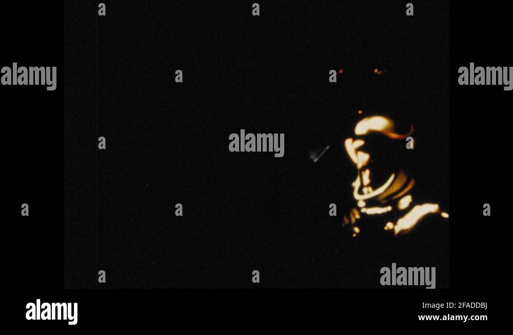 1960s: Astronaut adjusts camera in cockpit of command module. Sunlight ...