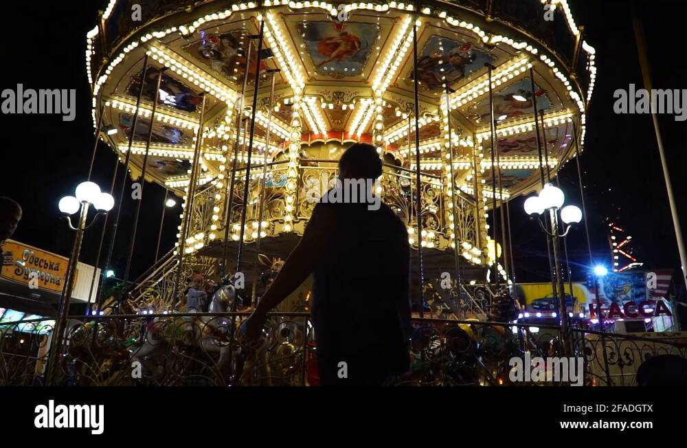 People walk around carousel on amusement park at night. Close up shot ...