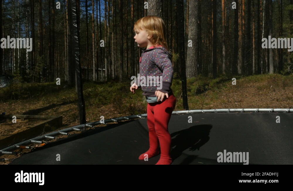 Kid, little girl, jumping on trampoline in park at summer day Stock ...