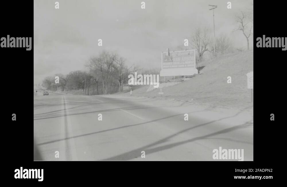 Cars pass on road and Ann Arbor sign on the side of the road - 1950 ...