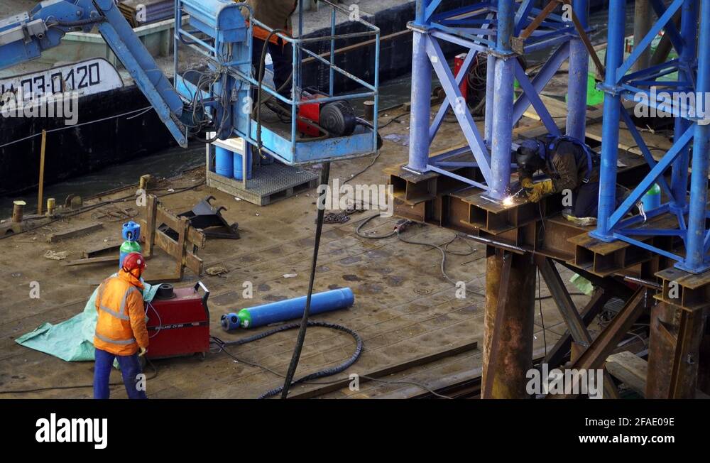 Construction workers welding metal of a column structure pillar with a ...
