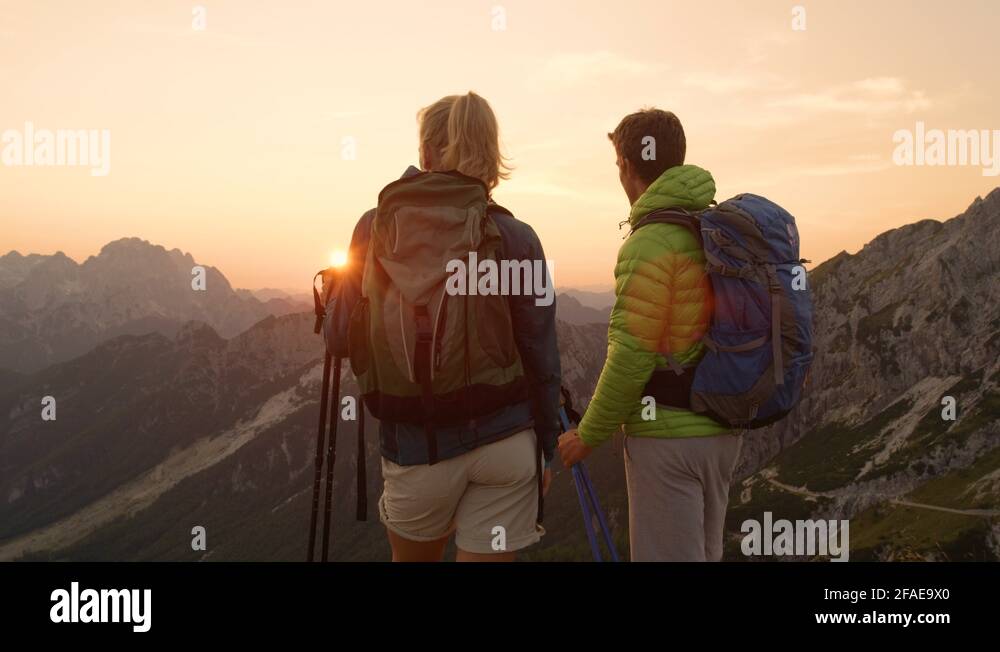 LENS FLARE: Young couple hiking in the stunning mountains high five at ...