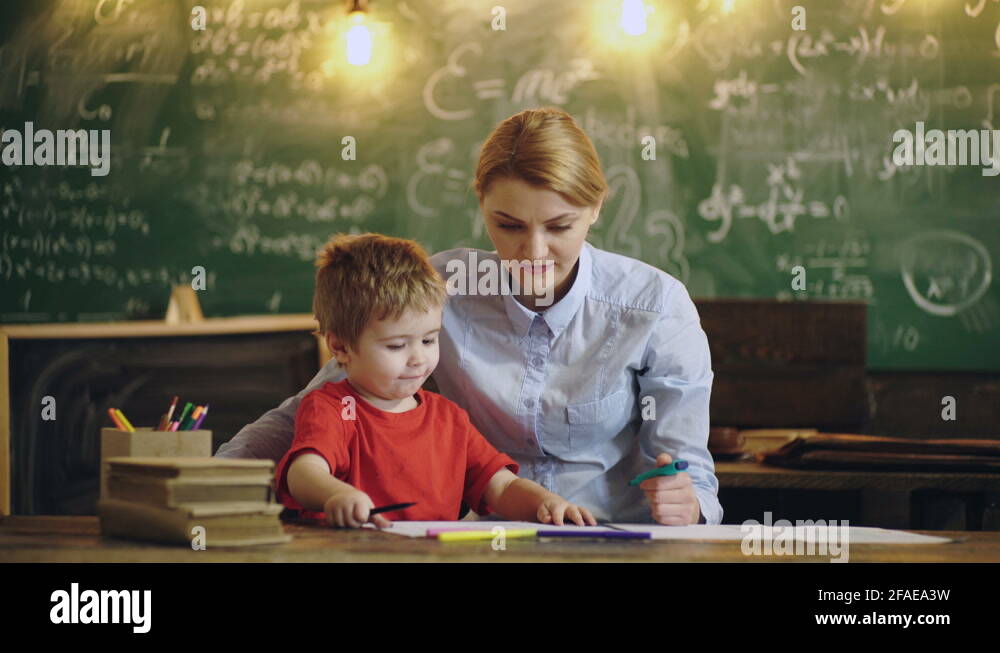 4K Primary school children drawing in the classroom with teacher ...