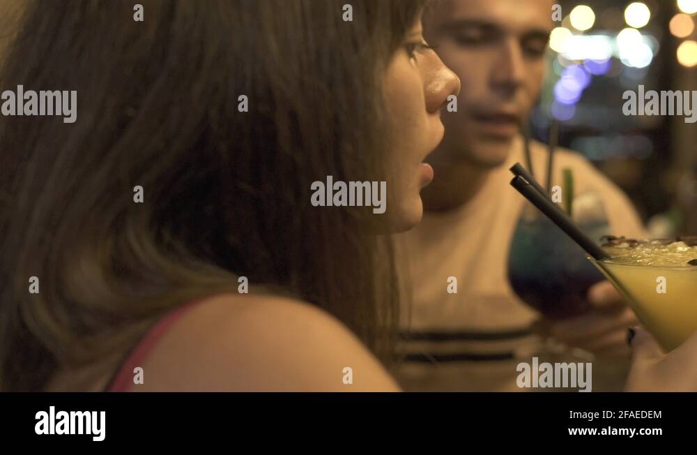 Young woman drinking from straw alcoholic cocktail together man in ...