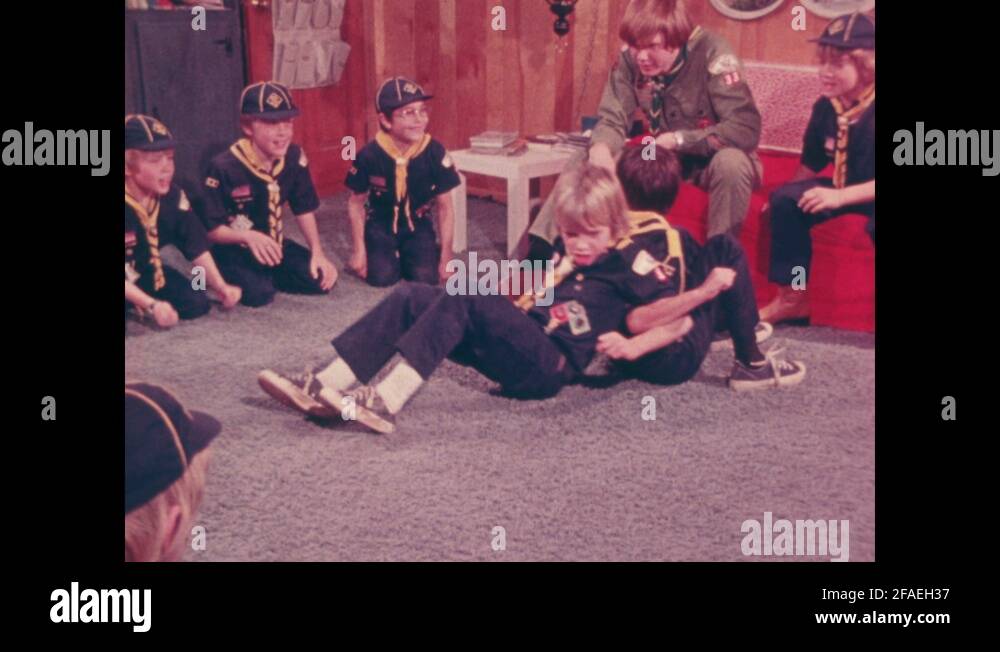 1970s: Cub scouts wrestle on floor in den. Cub scouts cheer on ...