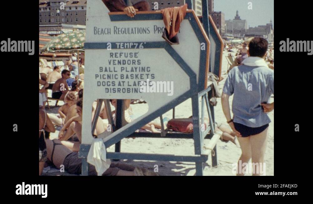 1930s: Lifeguard chair on beach. Women in bathing costumes wade into ...