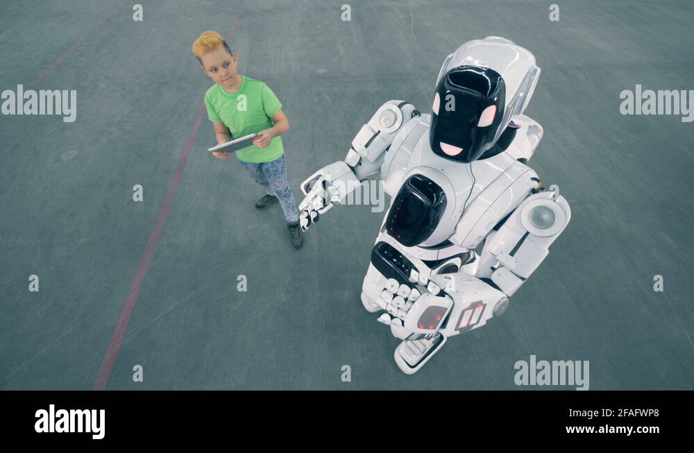 One robot moves while a boy controls. Futuristic humanoid robot Stock ...