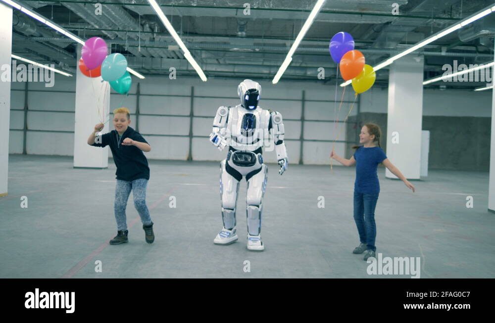 Android and children dance with balloons. Modern cyborg with children ...