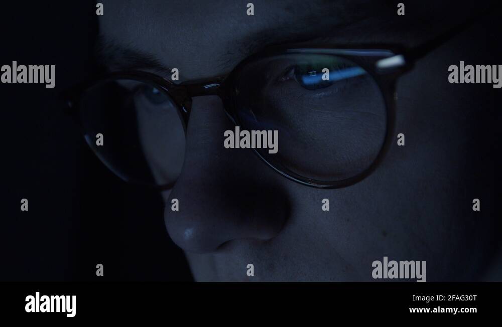 Young nerd hacker mans face closeup with computer monitor reflecting in ...