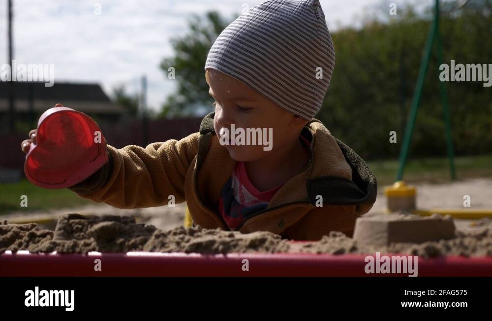 Cute Child Plays In Sandbox Outdoors. Makes Figures in Sand on Children ...