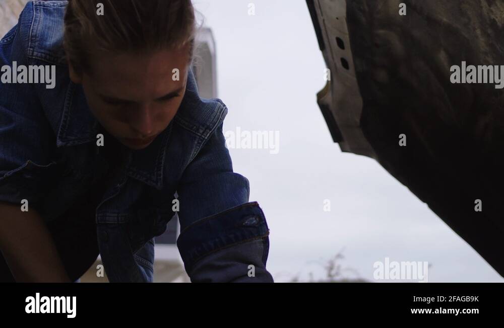 Low angle of a female checking under a bonnet for routine checks on a ...